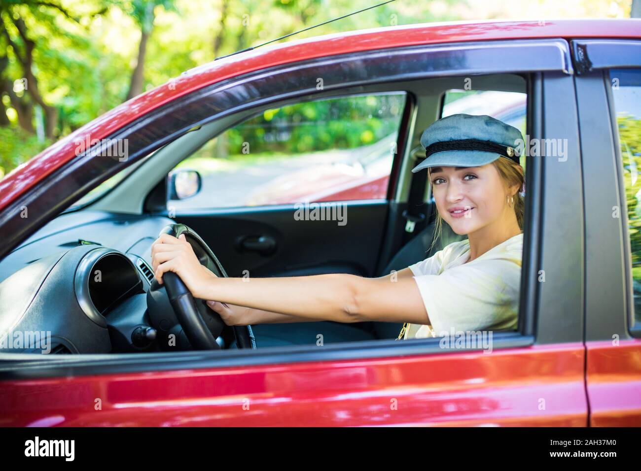 Happy woman driver behind the wheel red car Stock Photo - Alamy