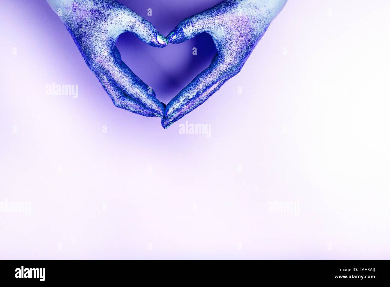 Female hand in blue glitter showing heart shape gesture. Golden ...