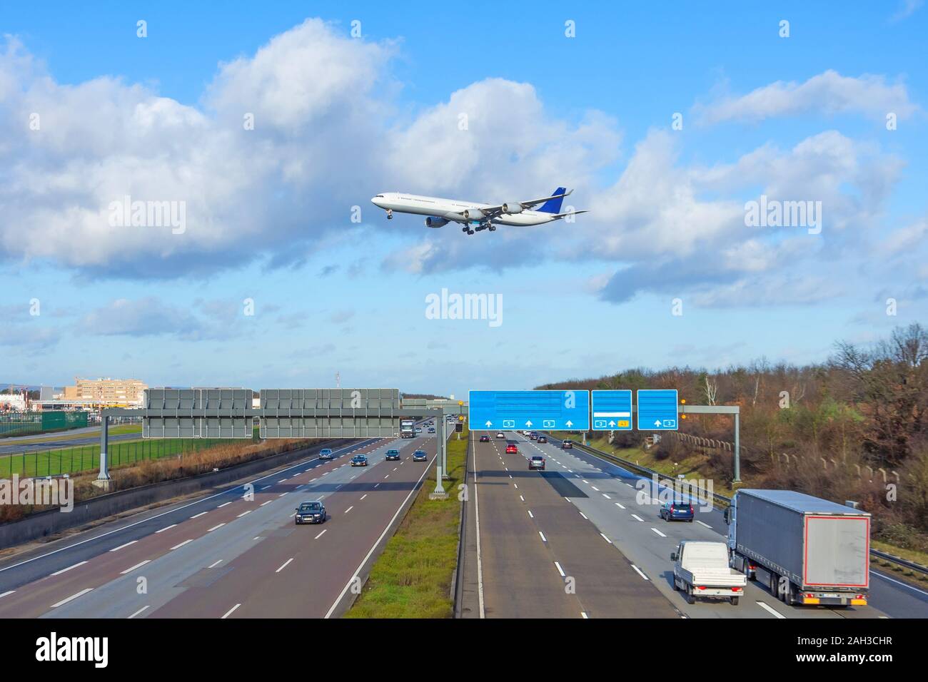 Landing airplane flies over a high-speed highway with cars in the city ...