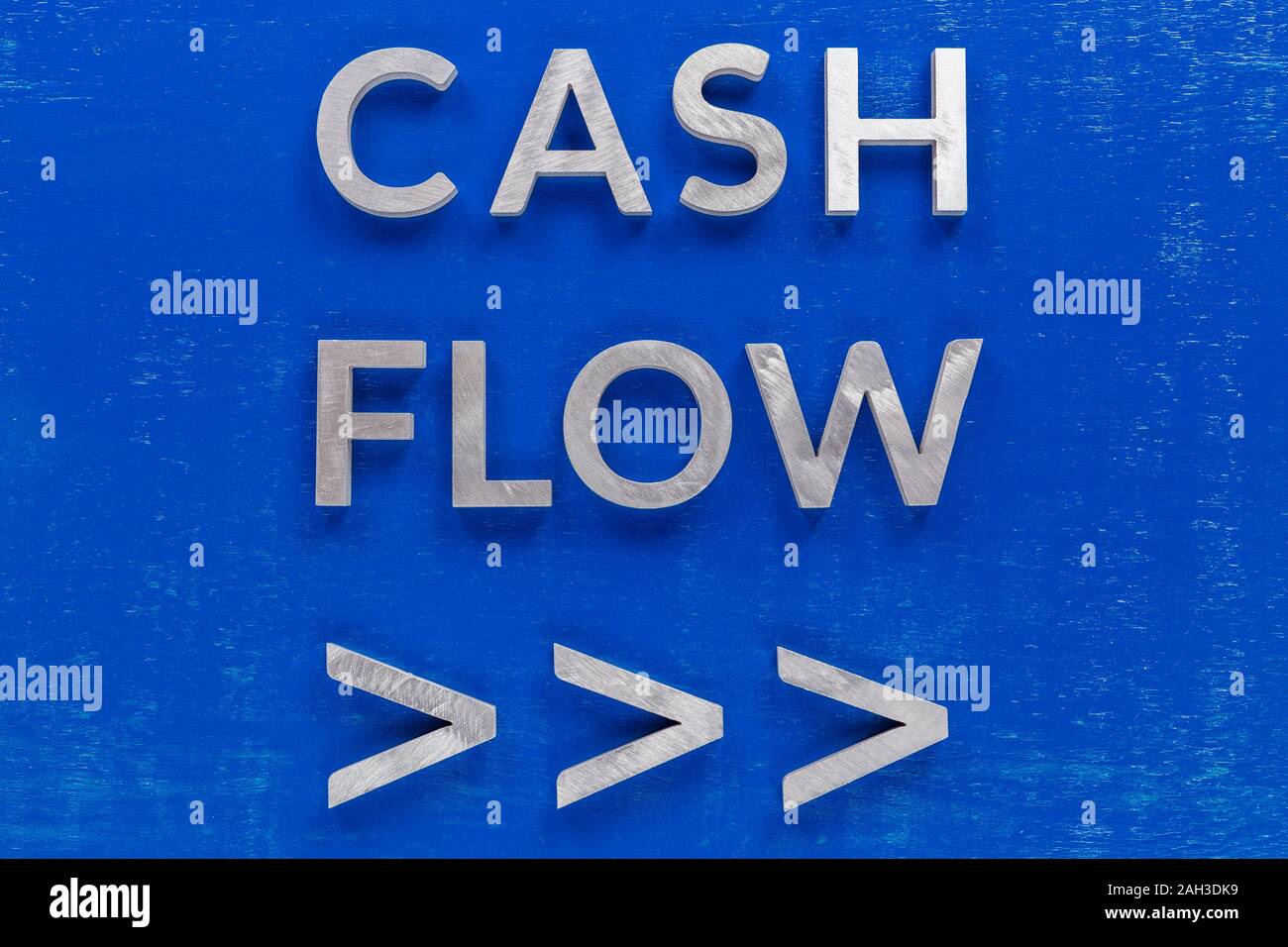 The words cash flow with arrows laid on blue painted board with thick ...