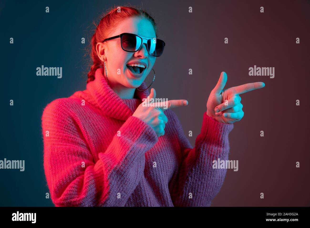 Pointing at side. Caucasian woman's portrait isolated on gradient ...