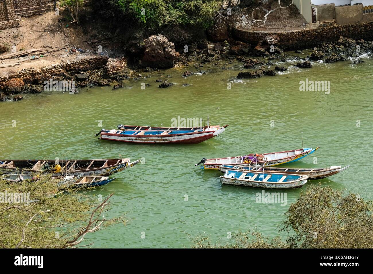 Colorful traditional fishing boats (canoes) rest at anchor in a small ...