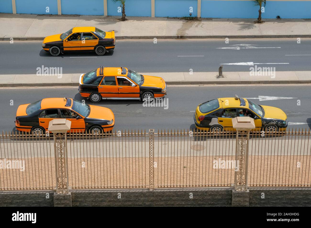 Yellow taxi cabs drive along a road in Dakar, the capital of Senegal ...
