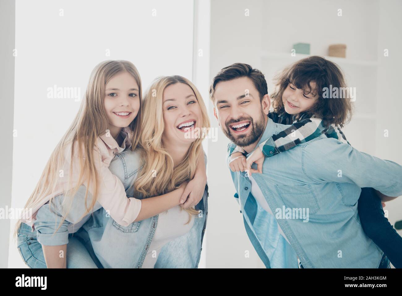 Photo of four members family hugging carry little children piggy back ...