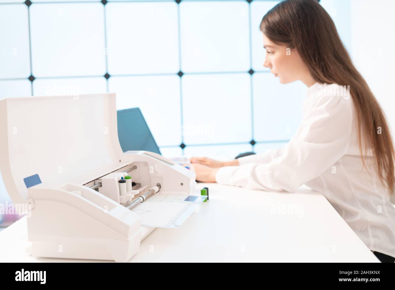 Young woman in the office of the printing company sets up a plotter for ...