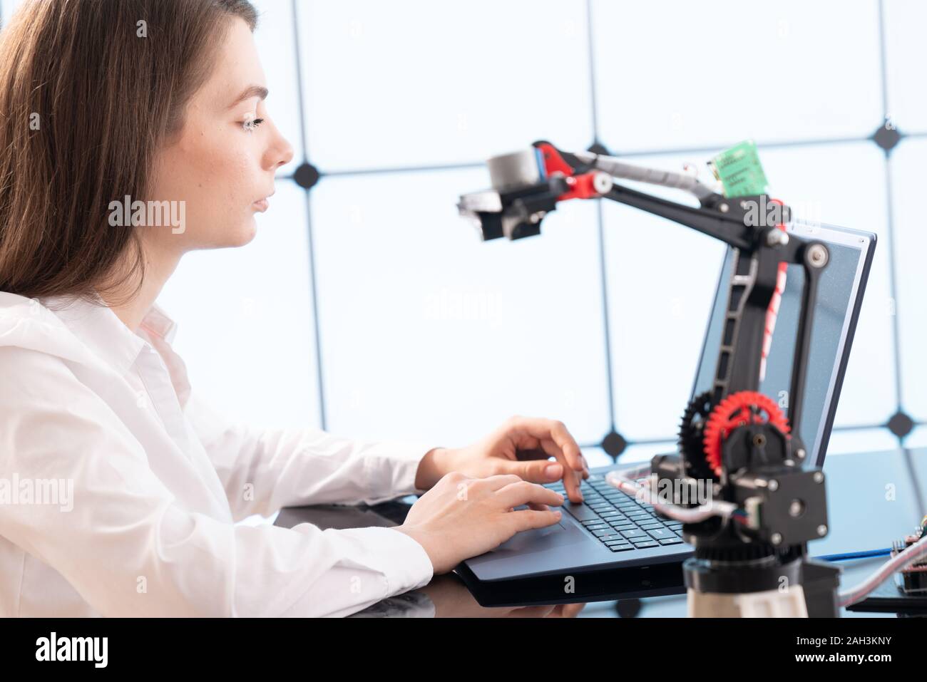 A young woman writes an algorithm for the robot arm. Science Research ...