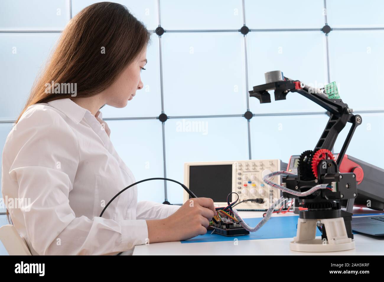 A young woman writes an algorithm for the robot arm. Science Research ...