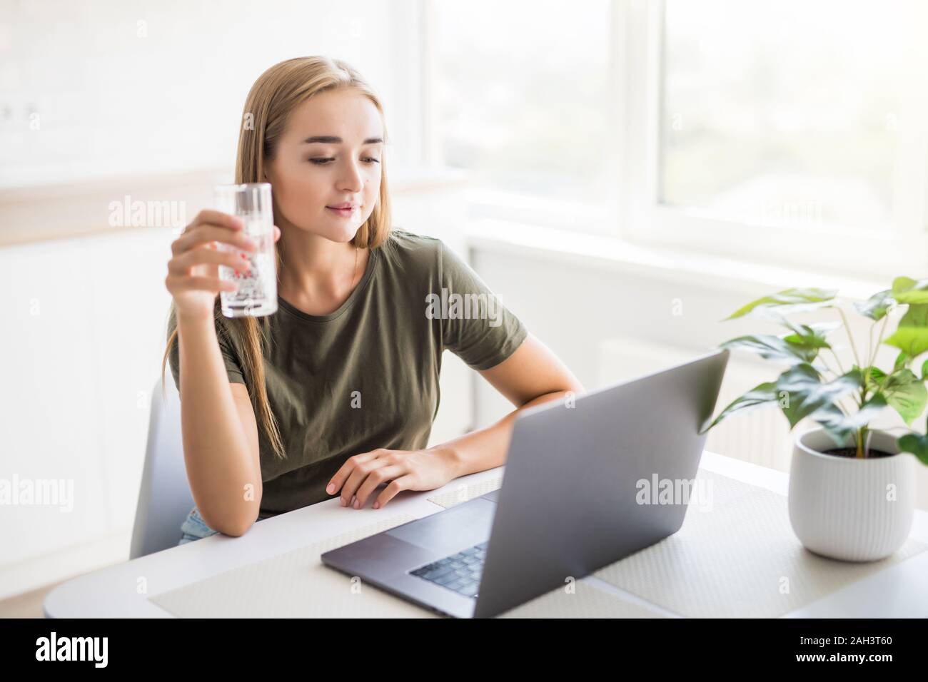 Woman Drinking from Water Glass while Typing at her Laptop Stock Photo ...