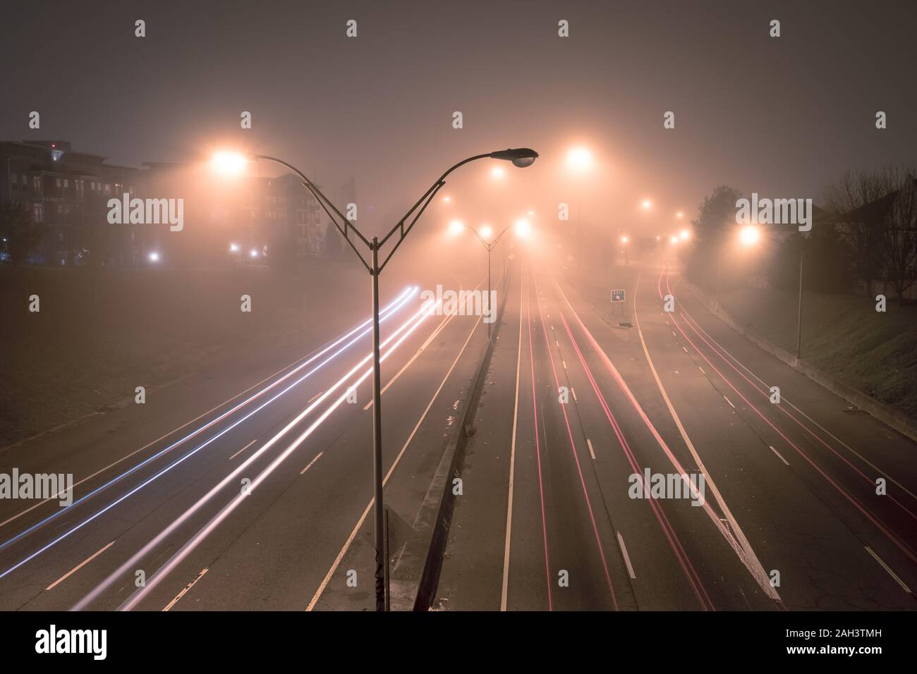 Highway at foggy night with bright trails of light from incoming and ...