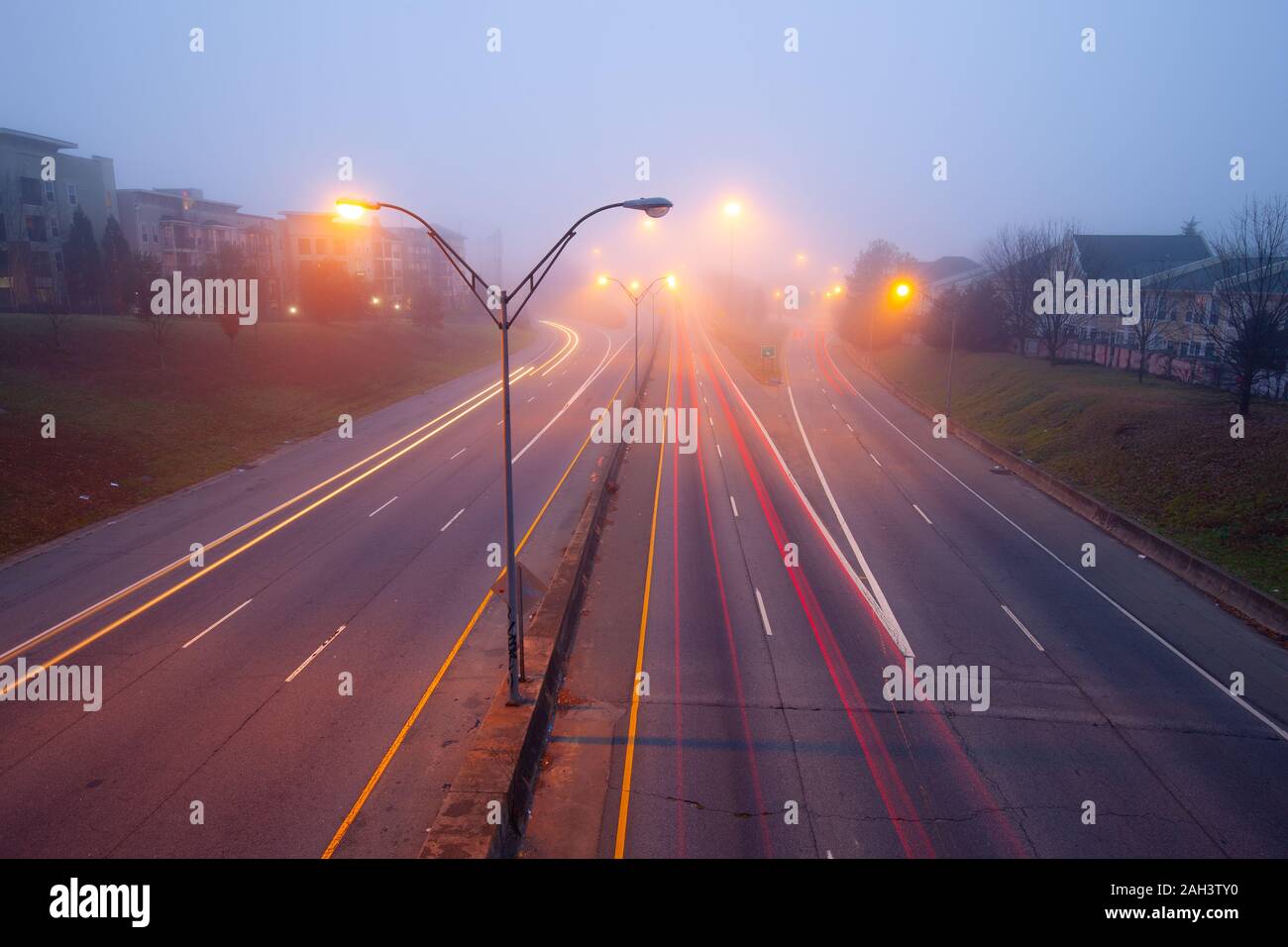 Highway at foggy night with bright trails of light from incoming and ...