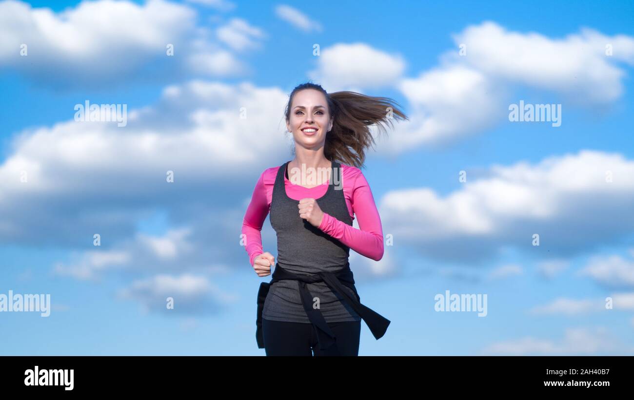 Woman jogging on a blue cloudy sky background. Healthy lifestyle ...