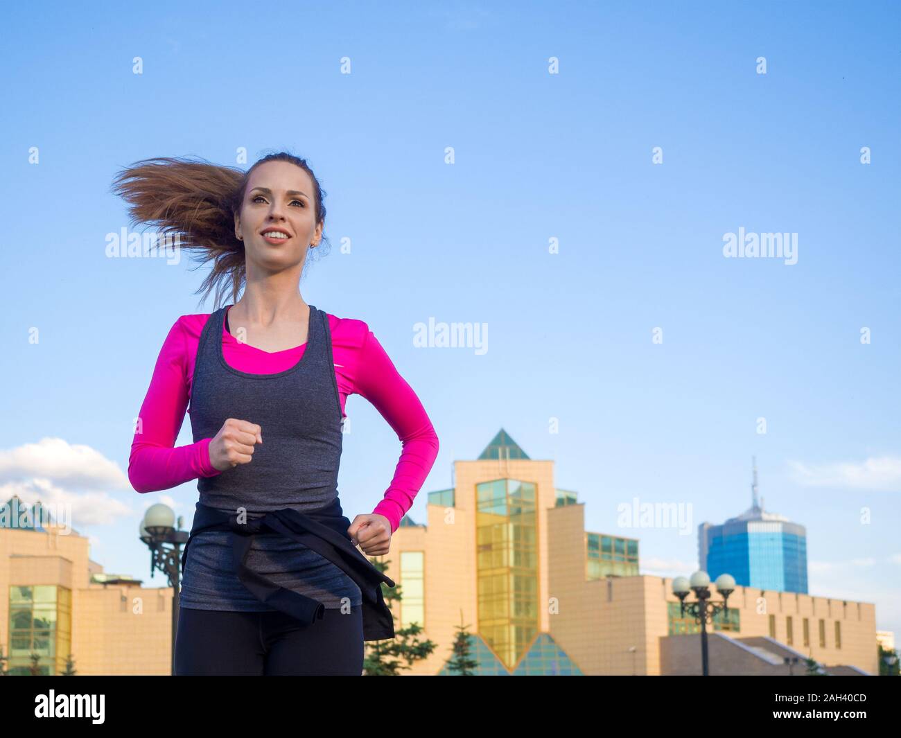 Woman running in streets of a town, training and exercising for trail ...