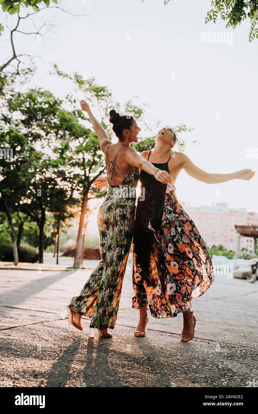 Two cheerful twin sisters dancing outdoors at sunset Stock Photo - Alamy