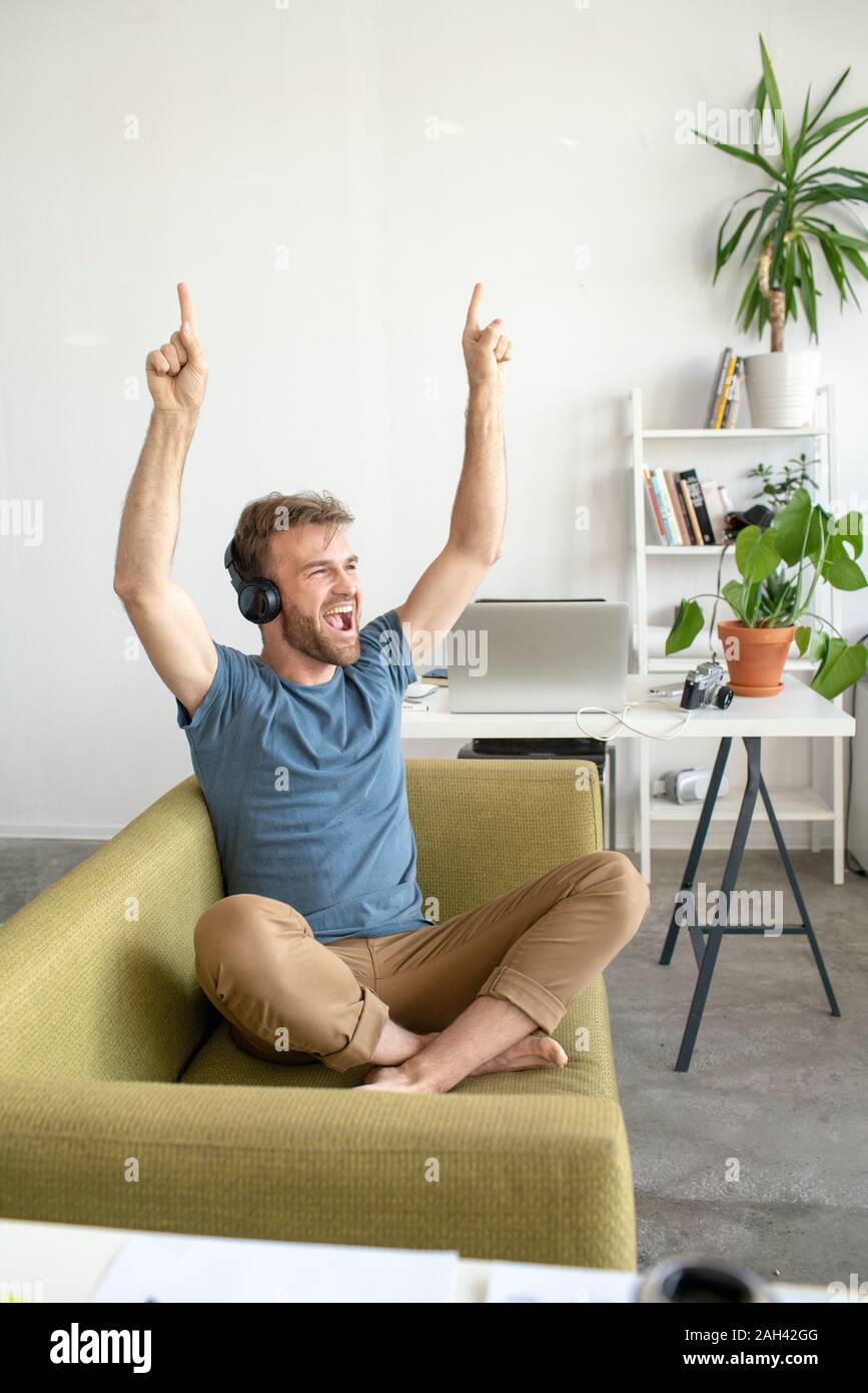 Excited man sitting on couch in office listening to music Stock Photo ...