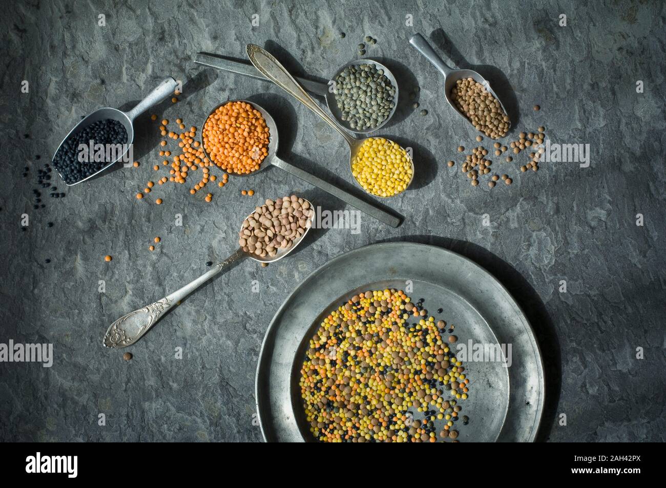 Plate and spoons of colorful lentils Stock Photo - Alamy