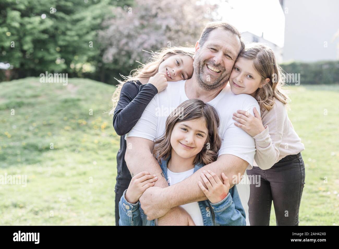 Portrait of happy father with three triplet daughters on a meadow Stock ...