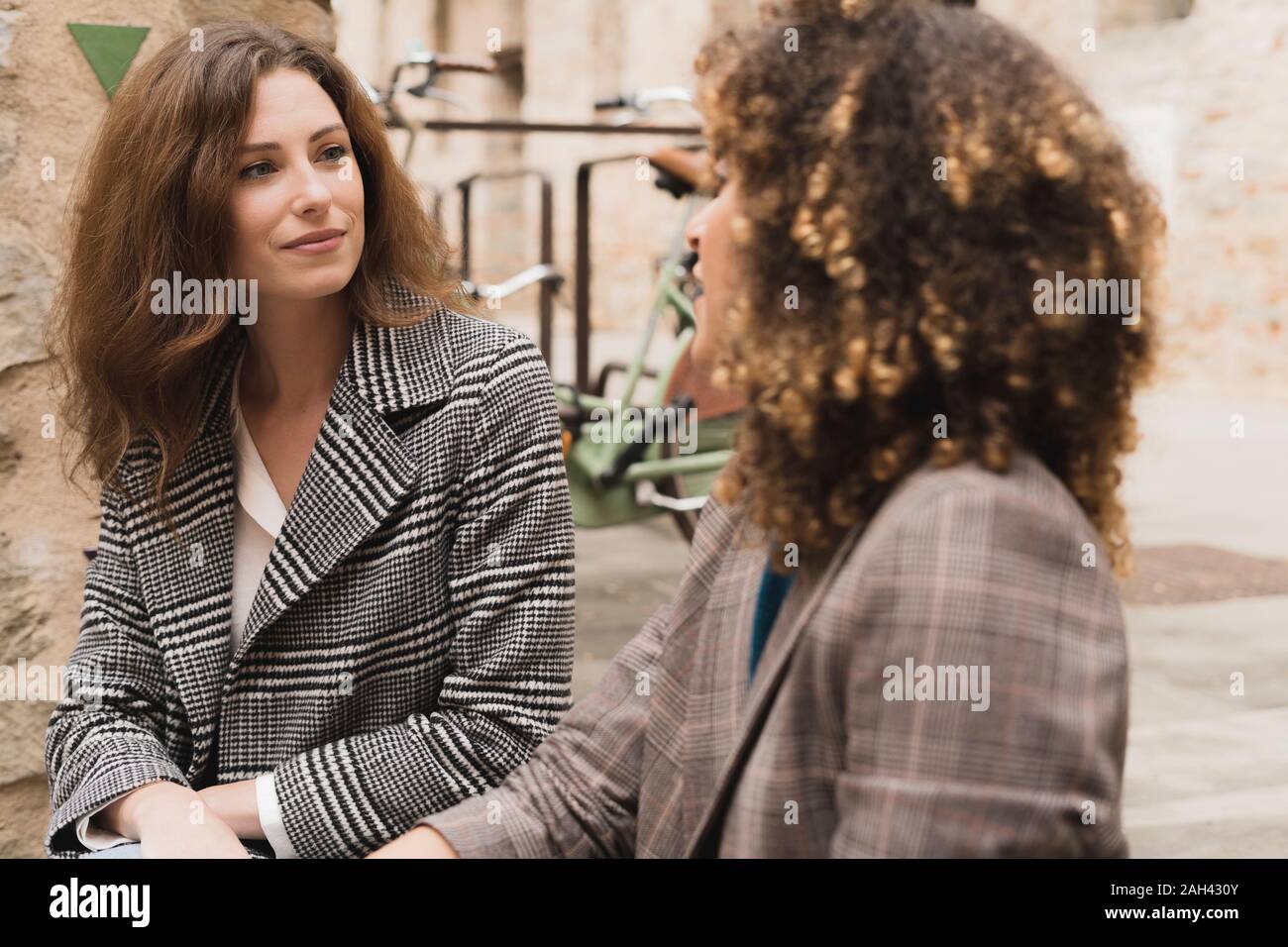Two women meeting and talking outdoors in the city Stock Photo - Alamy