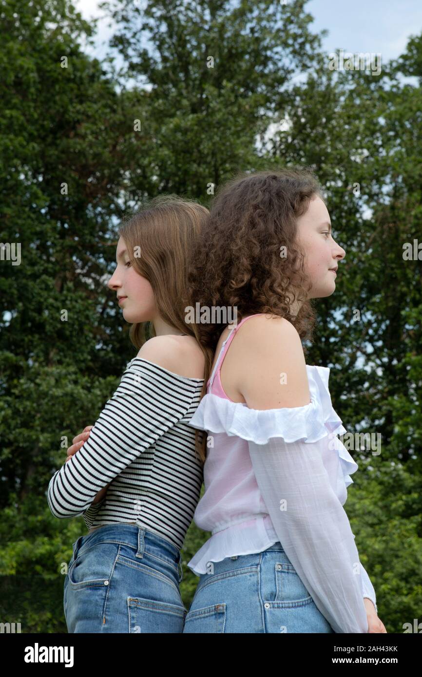 Two best friends standing back to back on a meadow Stock Photo - Alamy