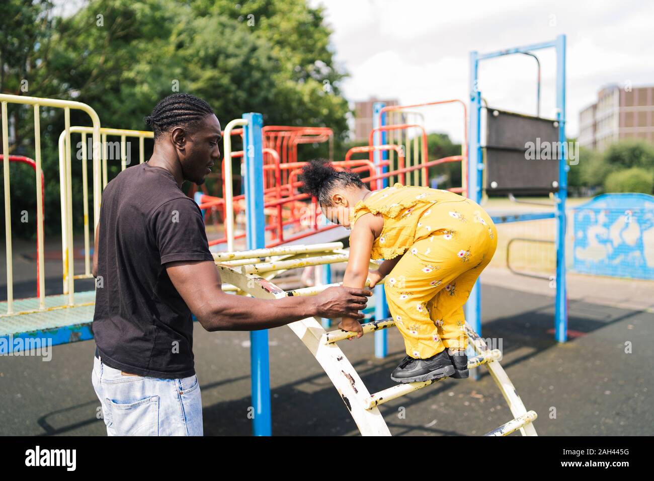 Father helping daughter climbing up a ladder on a playground Stock ...