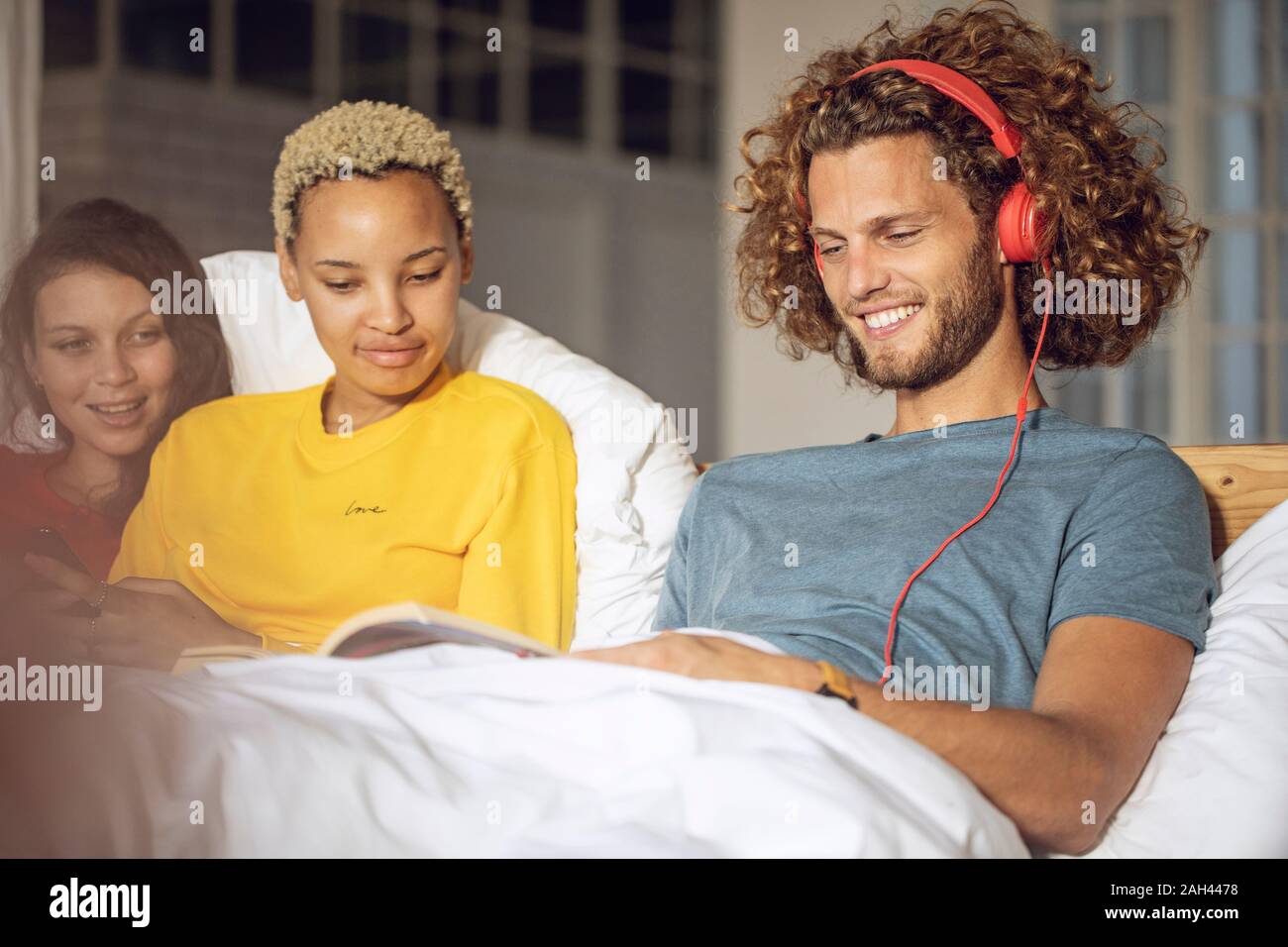 Happy friends relaxing in bed at home Stock Photo - Alamy