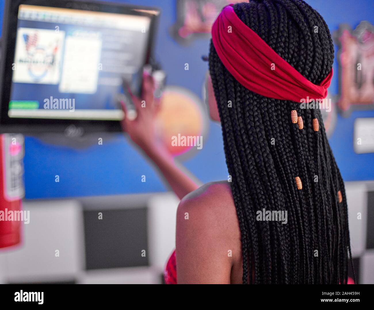 Young woman with braided hairstyle checking the orders on a screen ...