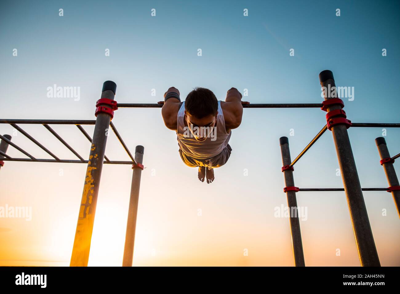 Young man practicing calisthenics at an outdoor gym at sunrise Stock ...