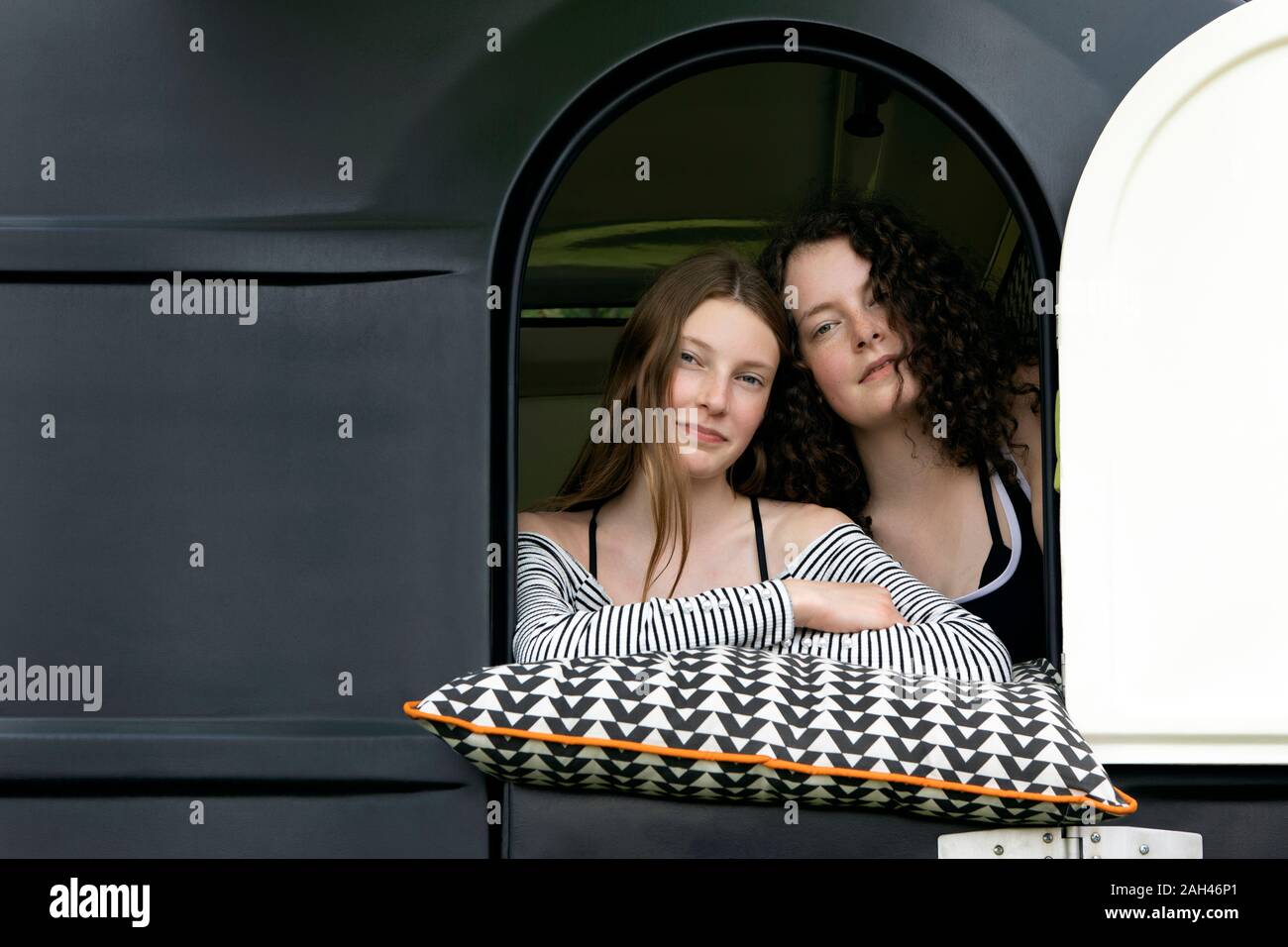 Portrait of two best friends looking out of caravan Stock Photo - Alamy