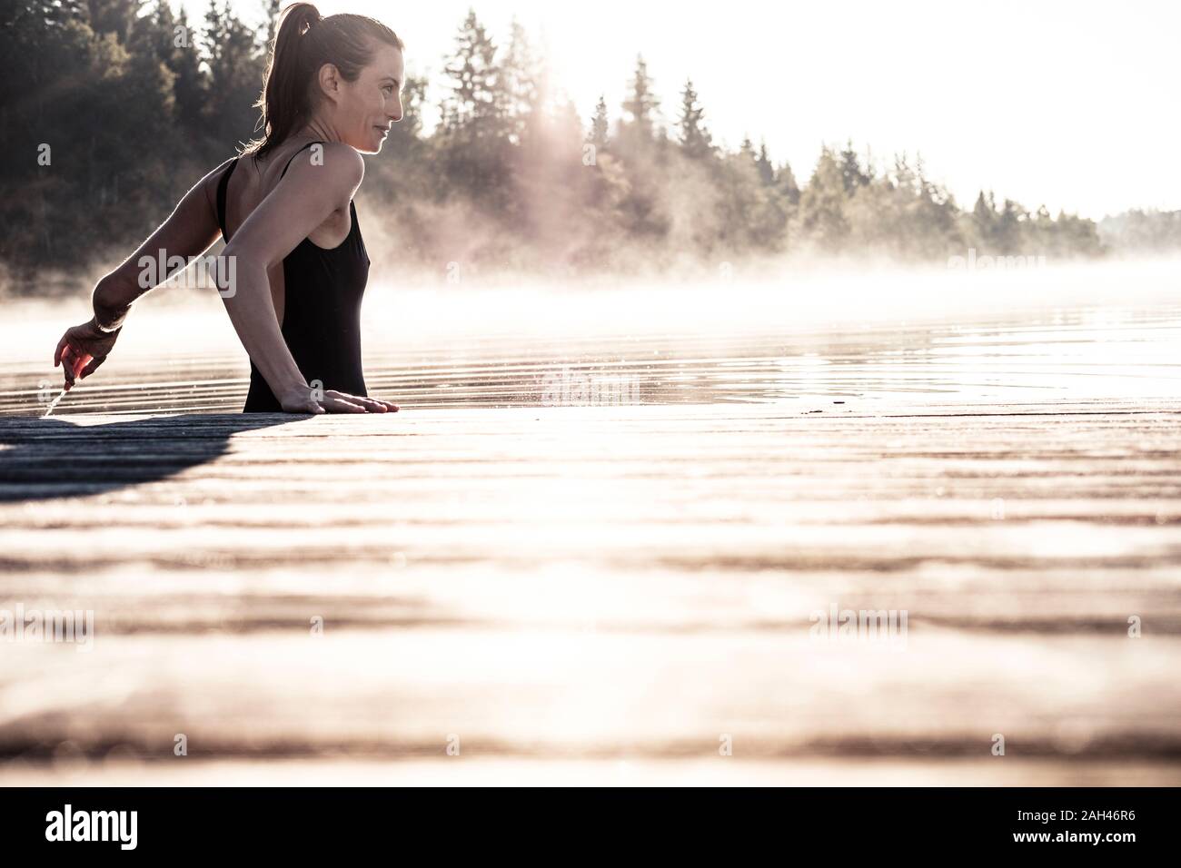 Woman wearing black swimsuit bathing in a lake at morning mist Stock ...