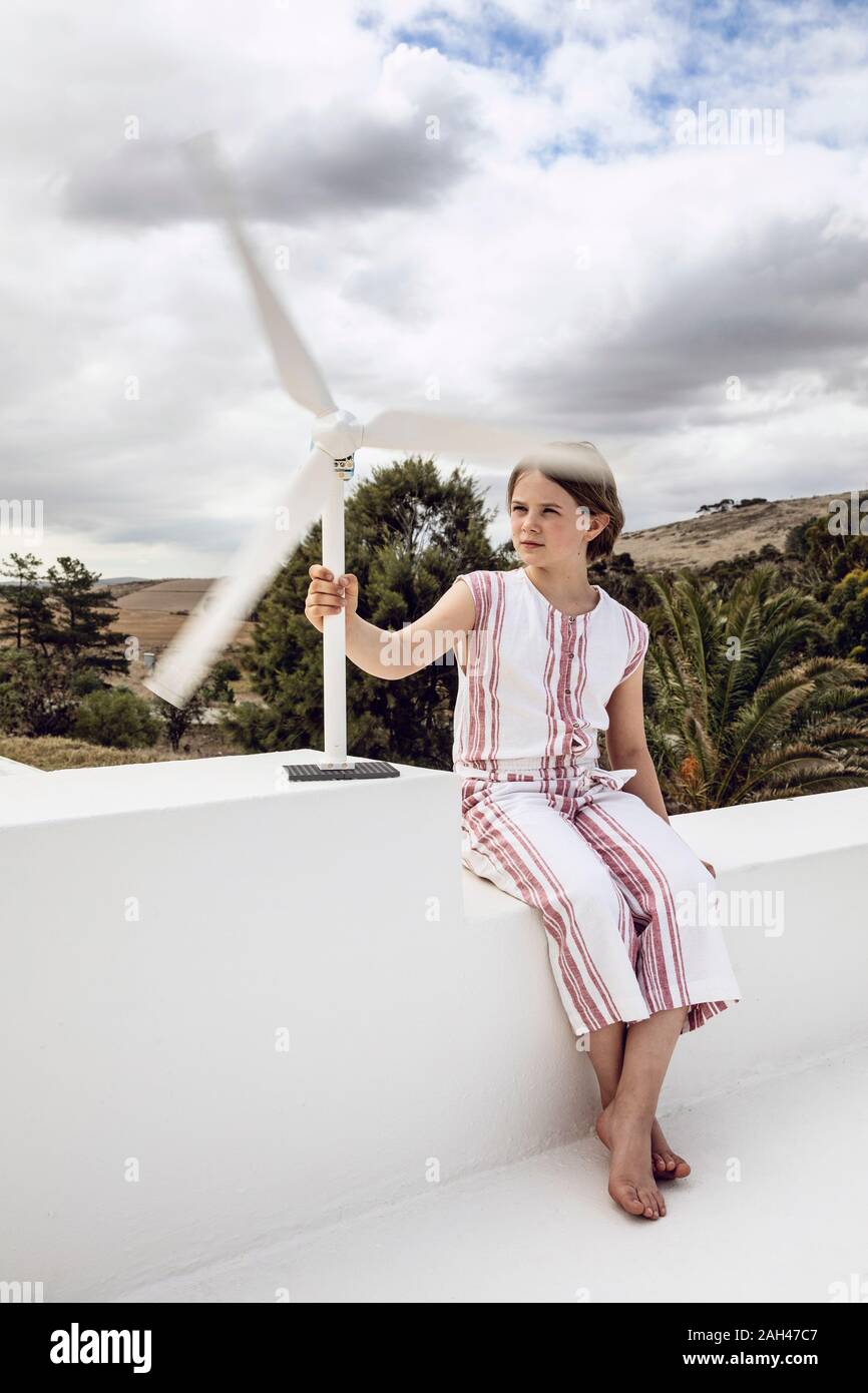 Girl looking at small wind turbine on white wall Stock Photo - Alamy