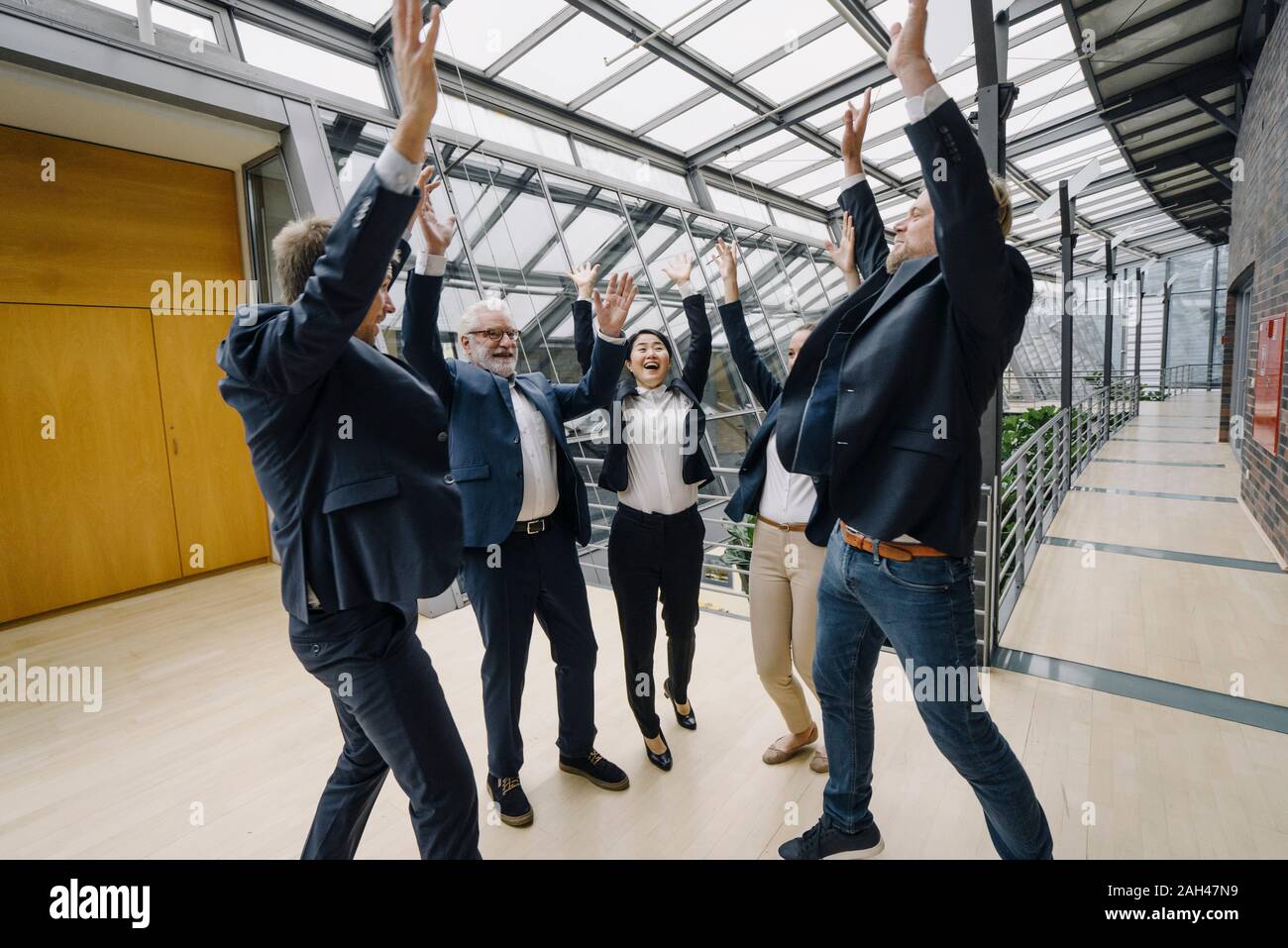 Happy business people cheering in modern office building Stock Photo ...