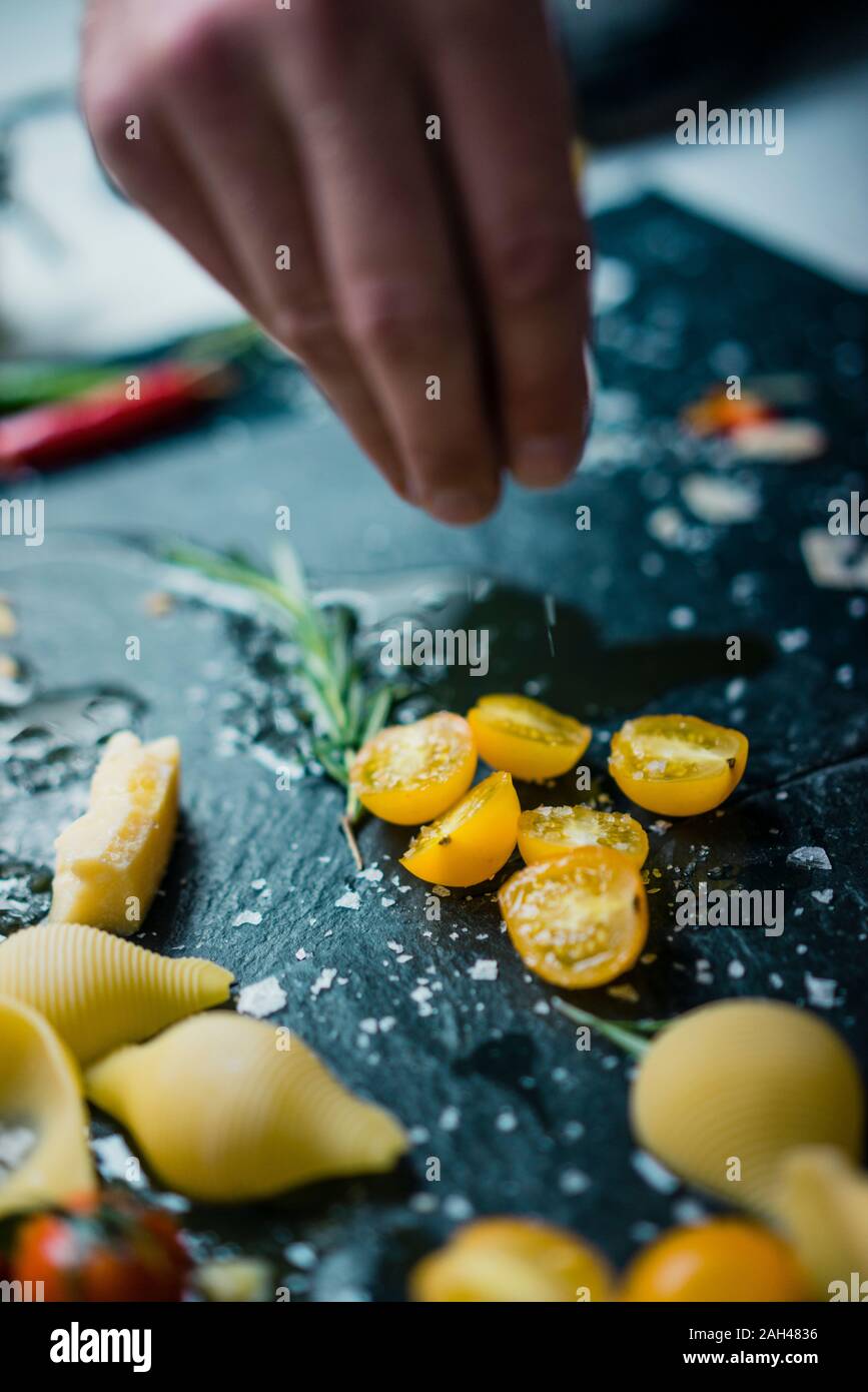 Hand seasoning chopped tomatoes on platter with pasta Stock Photo - Alamy
