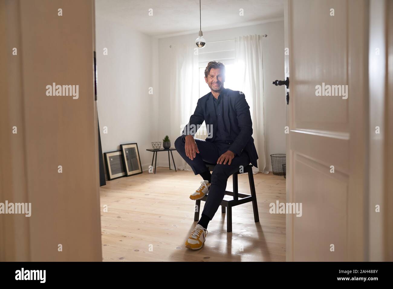 Portrait of smiling mature man sitting on stool at home Stock Photo - Alamy