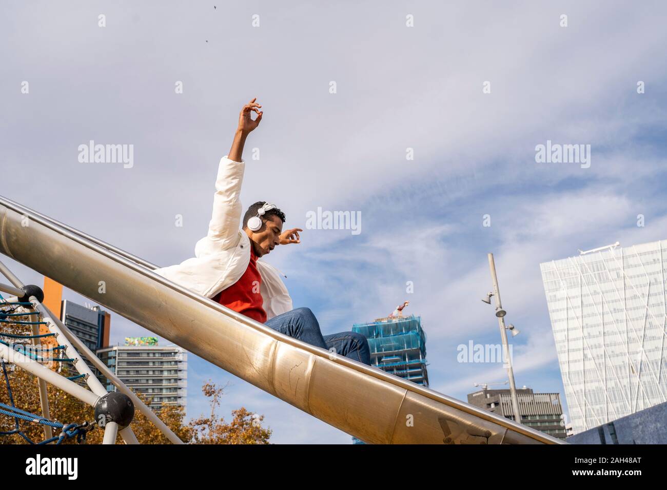Young man sliding on a playground Stock Photo - Alamy