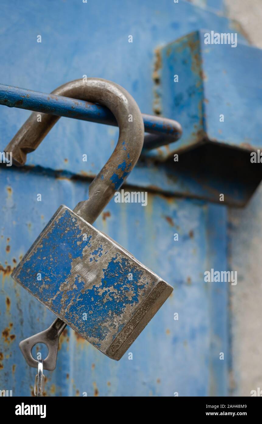 Large padlock hangs on the metal door handle. An open padlock with a ...