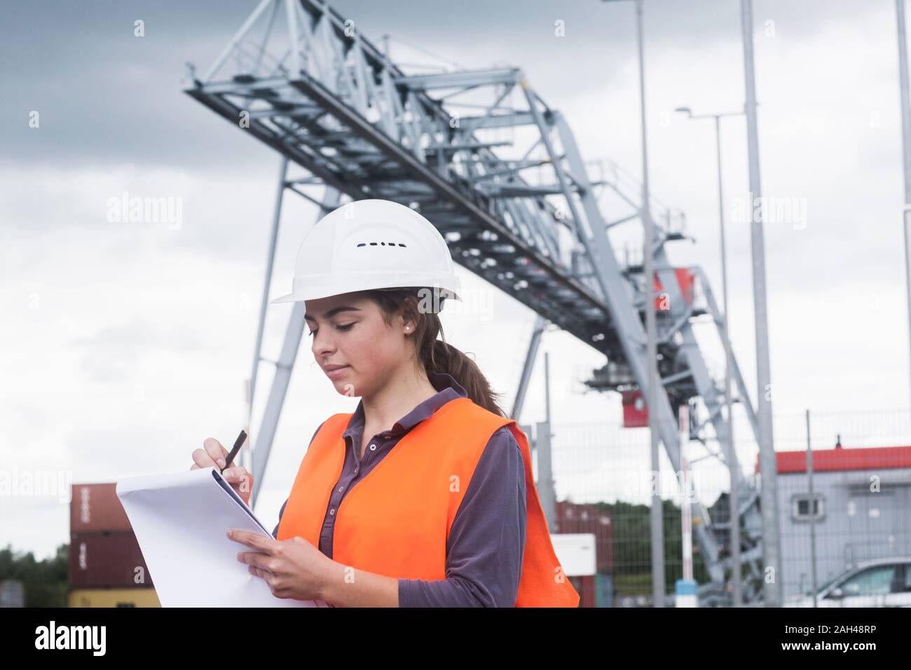 Female worker with clipboard taking notes on industrial site Stock ...