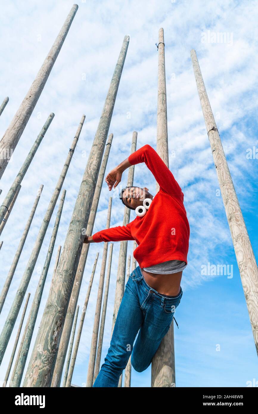 Young man moving and dancing between wood poles Stock Photo - Alamy