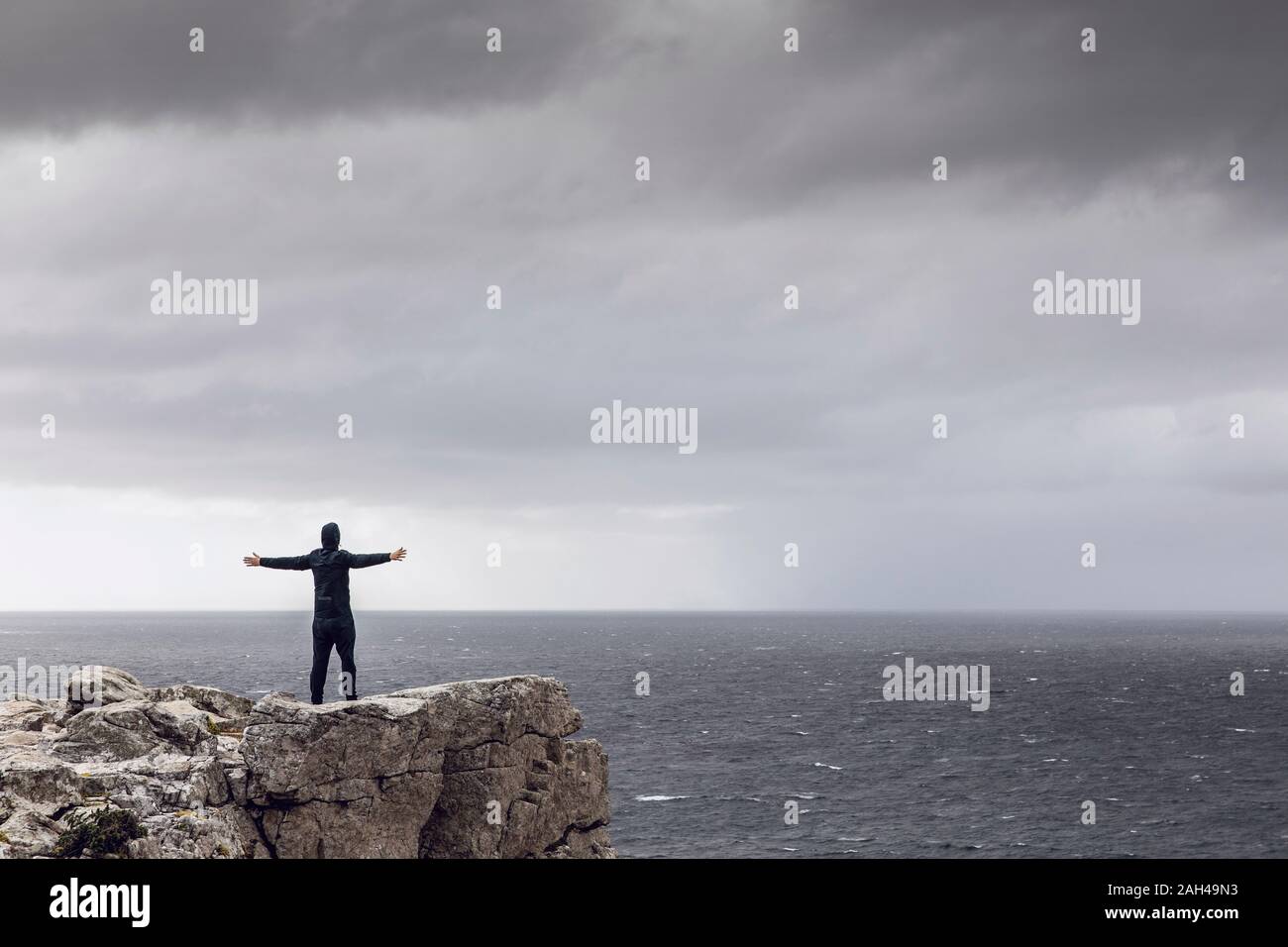 Back view of man standing on rocky cliff looking at horizon, Cape Point ...
