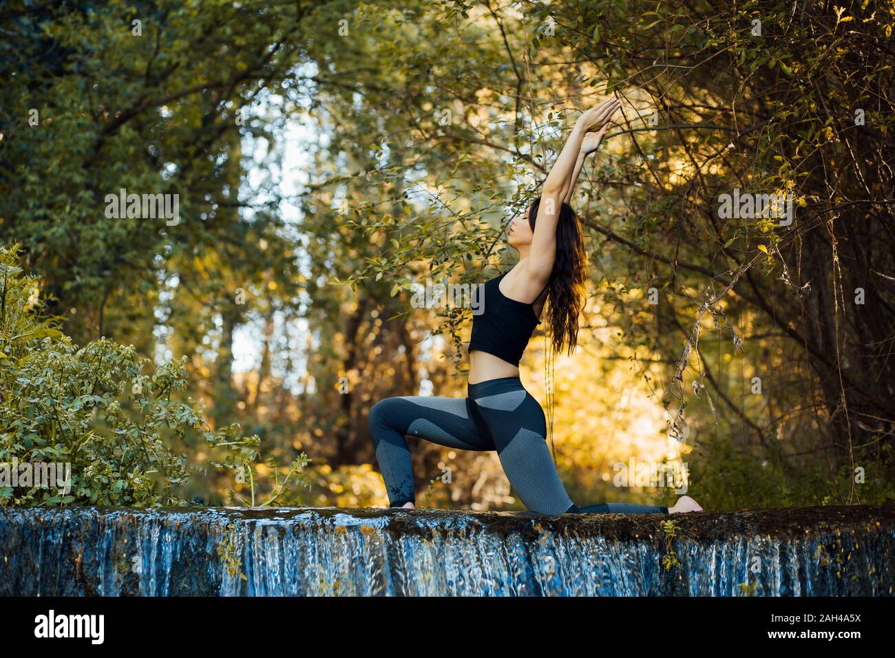 Young woman practicing yoga on a waterfall, bending over back Stock ...