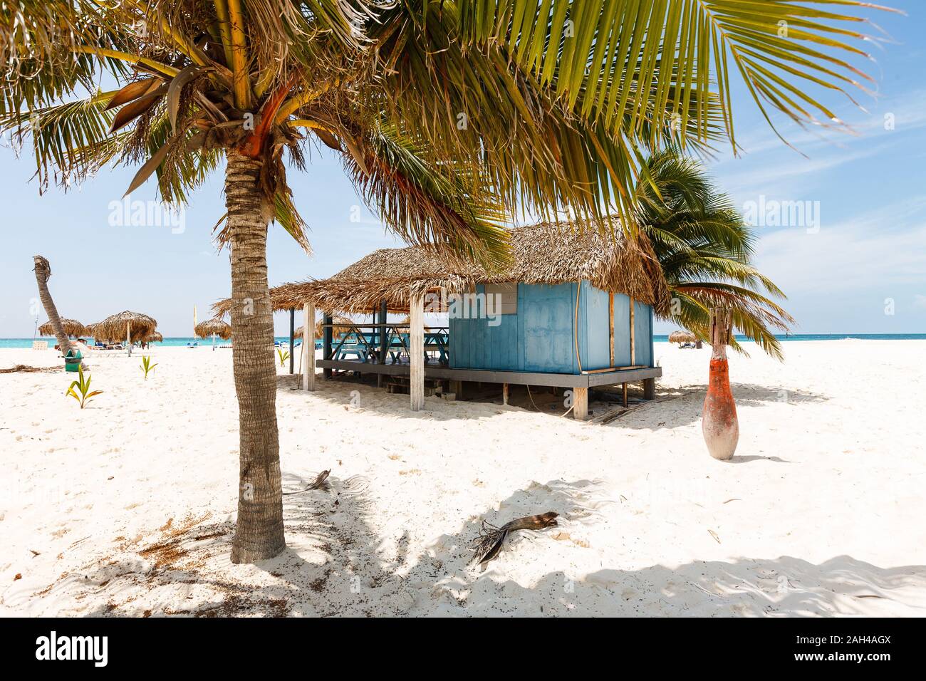 Blue beach house with small veranda, thatched roof standing on beach ...