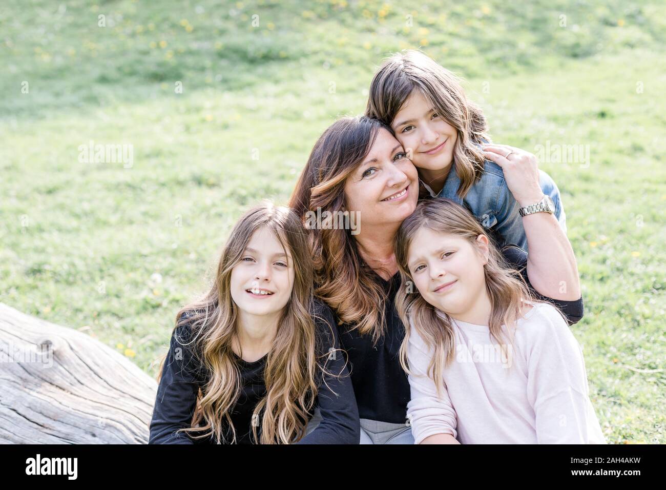 Portrait of smiling mother with three triplet daughters on a meadow ...