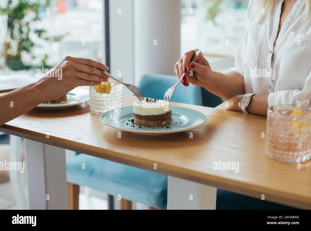 Anonymous young women sharing a cake at coffee shop Stock Photo - Alamy
