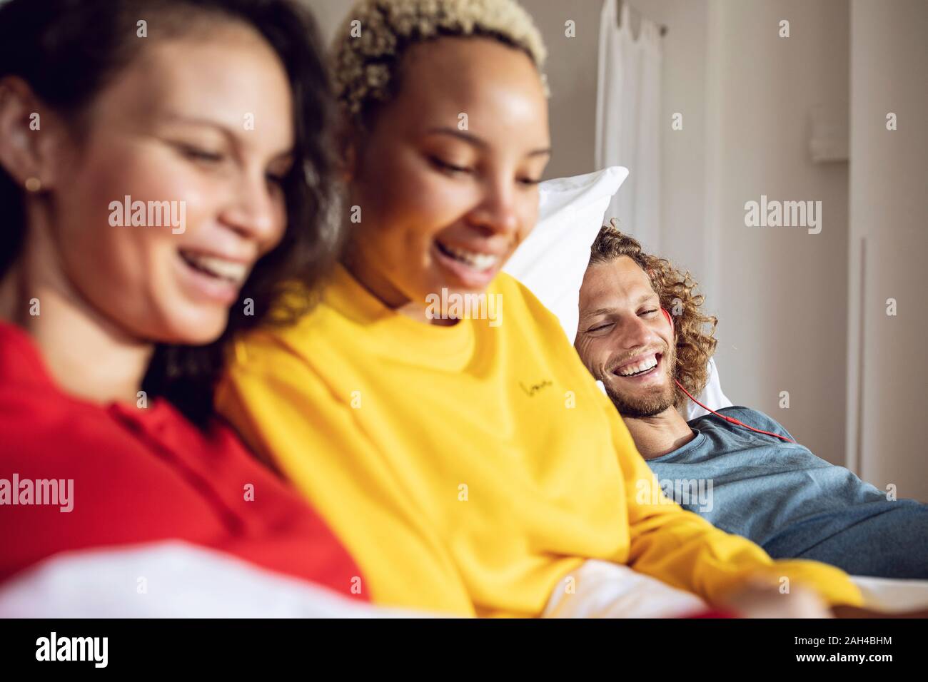 Happy friends relaxing in bed at home Stock Photo - Alamy