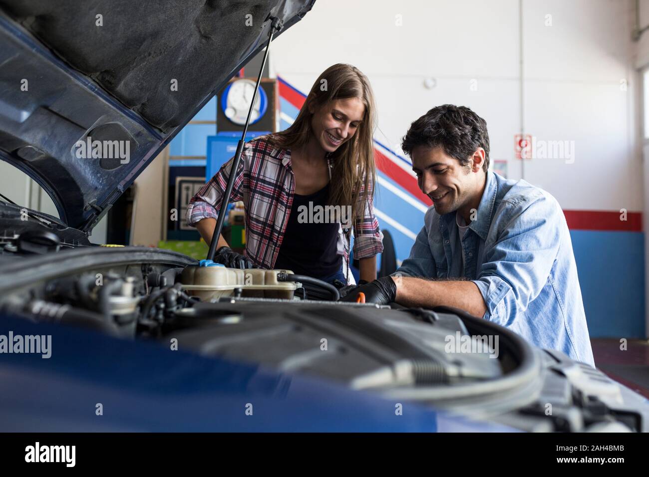 Cheerful man and young woman working together on car repair service and ...