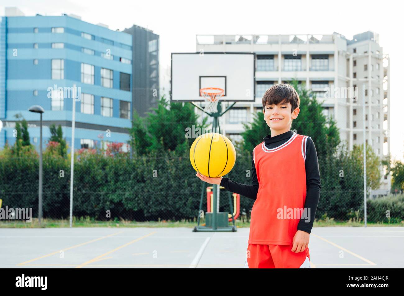 Portrait of smiling boy with basketball on outdoor court Stock Photo ...