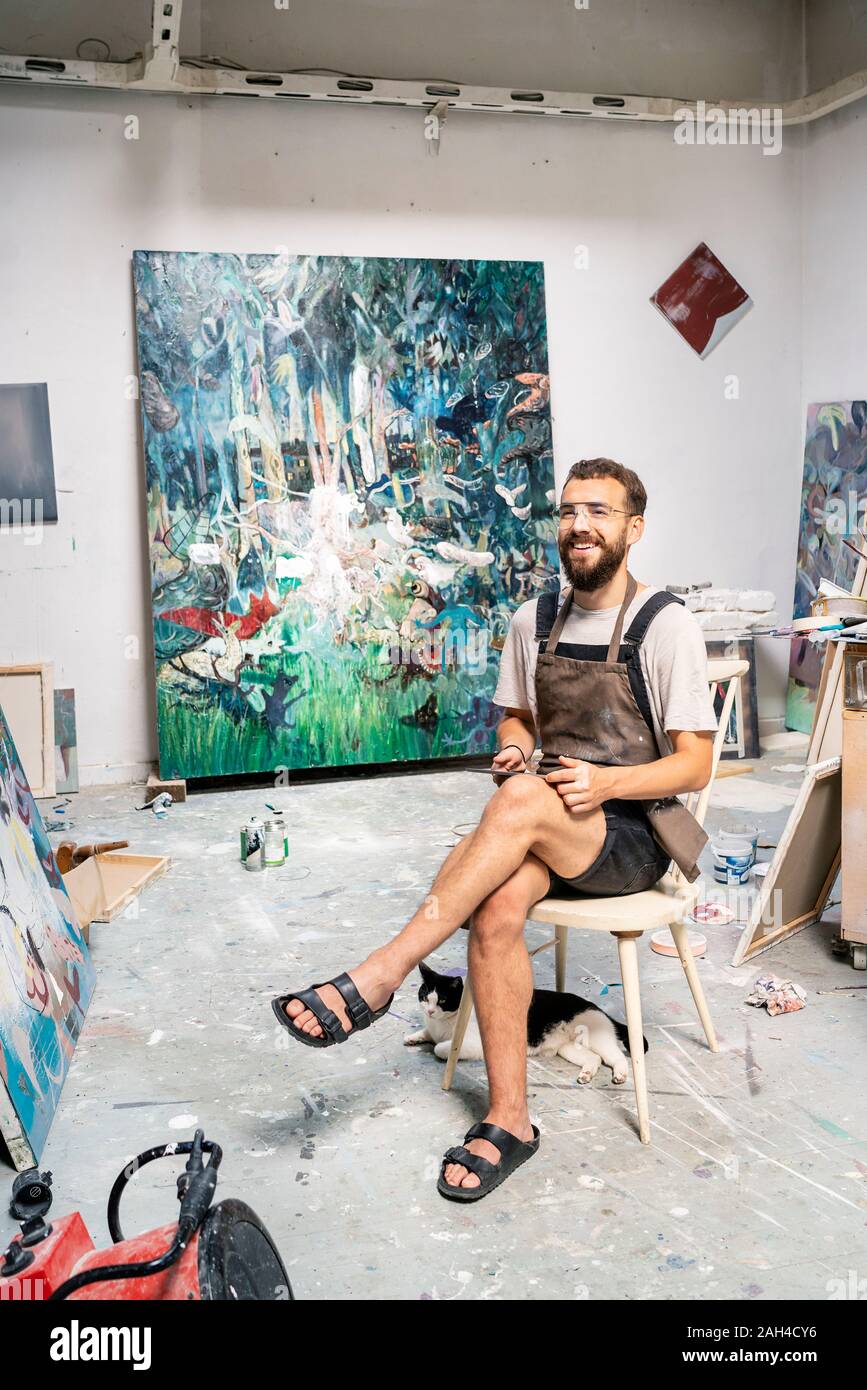 Artist sitting in his studio, laughing Stock Photo - Alamy