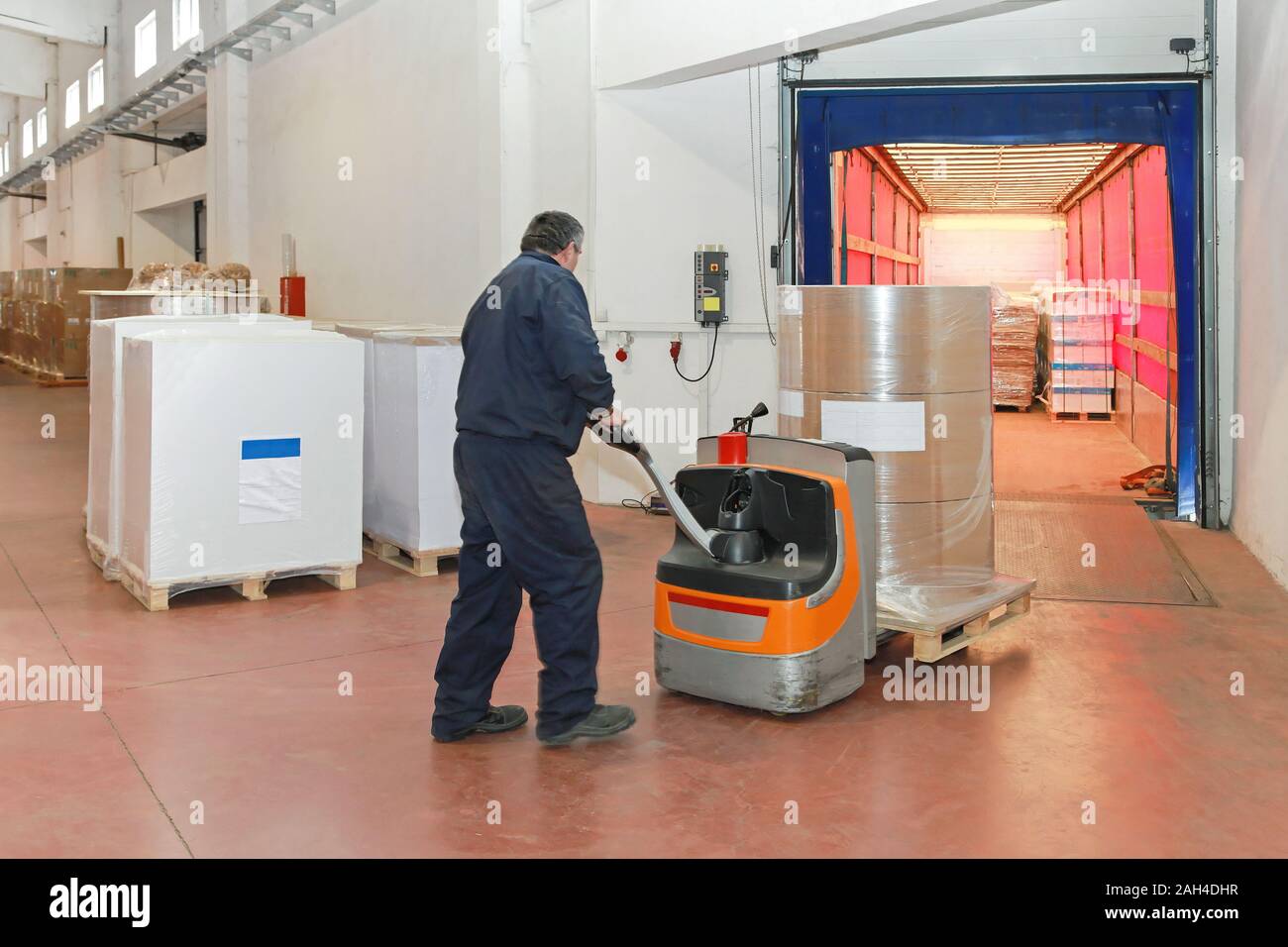 Worker loading paper rolls in to lorry with forklift Stock Photo - Alamy