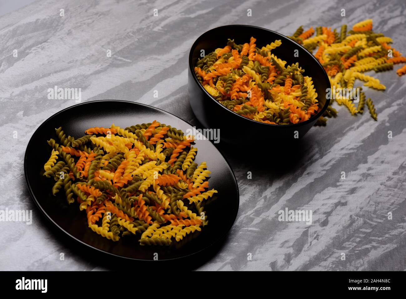 delicious colorful Italian pasta in two black ceramic plates on grey ...