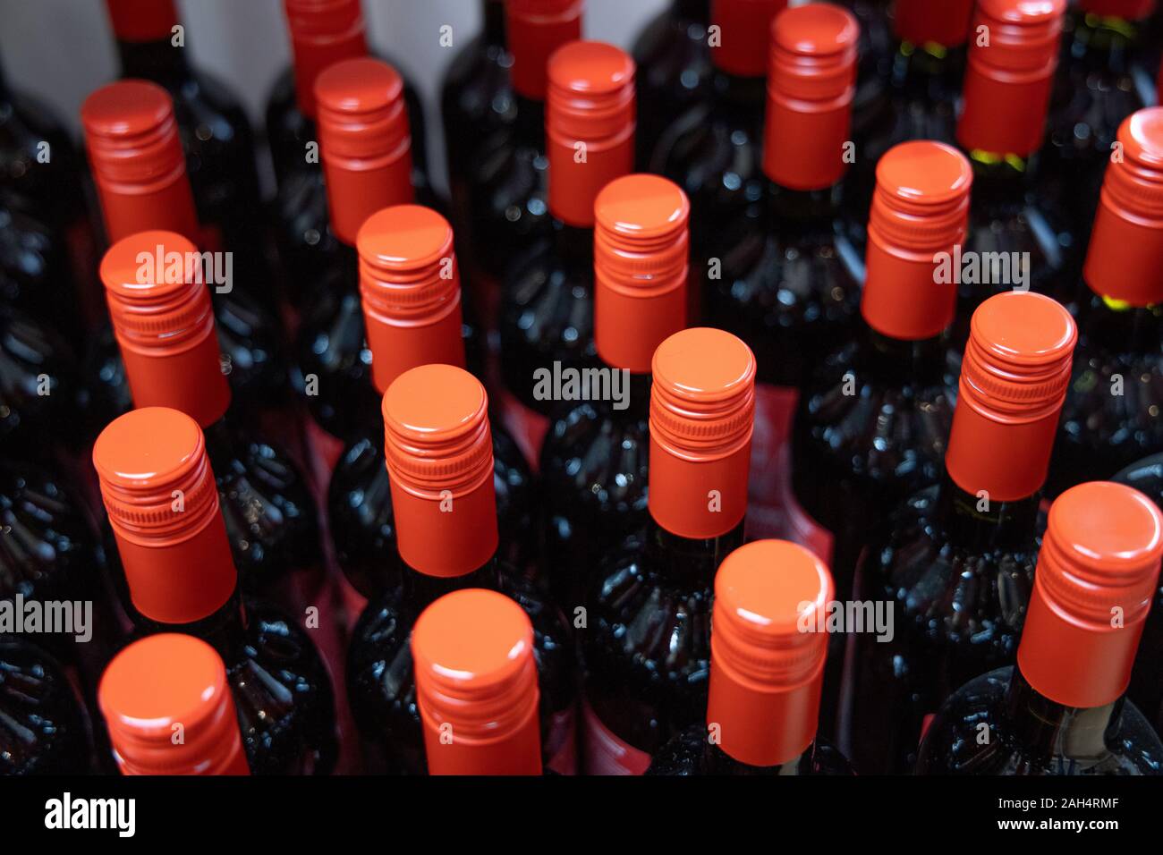 Metal corks of bright red color on glass bottles in rows. Drinks, food ...