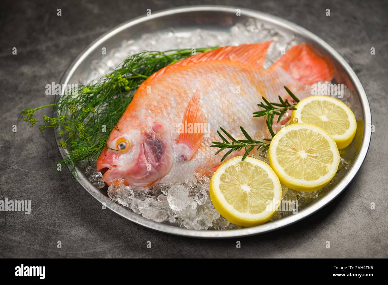 Fresh fish on ice with herbs spices rosemary and lemon / Raw fish red ...