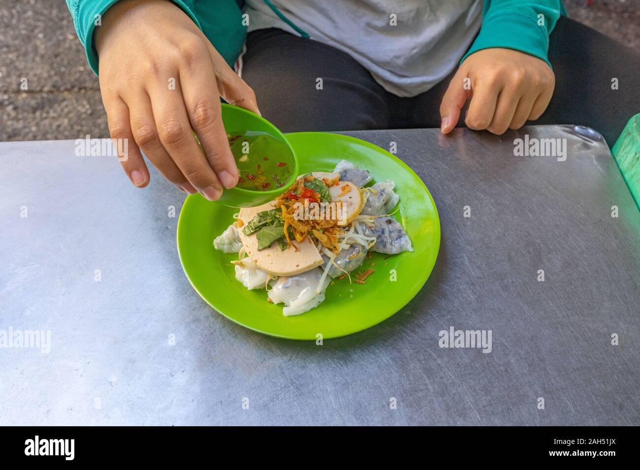 Woman having Vietnamese steamed rice rolls with chili fish sauce Stock ...